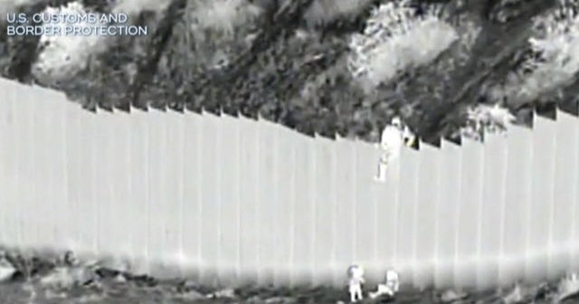 Video shows smugglers dropping young kids over border barrier - CBS News