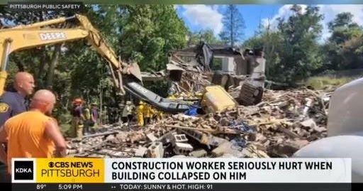Worker rescued from excavator after building partially collapses during ...